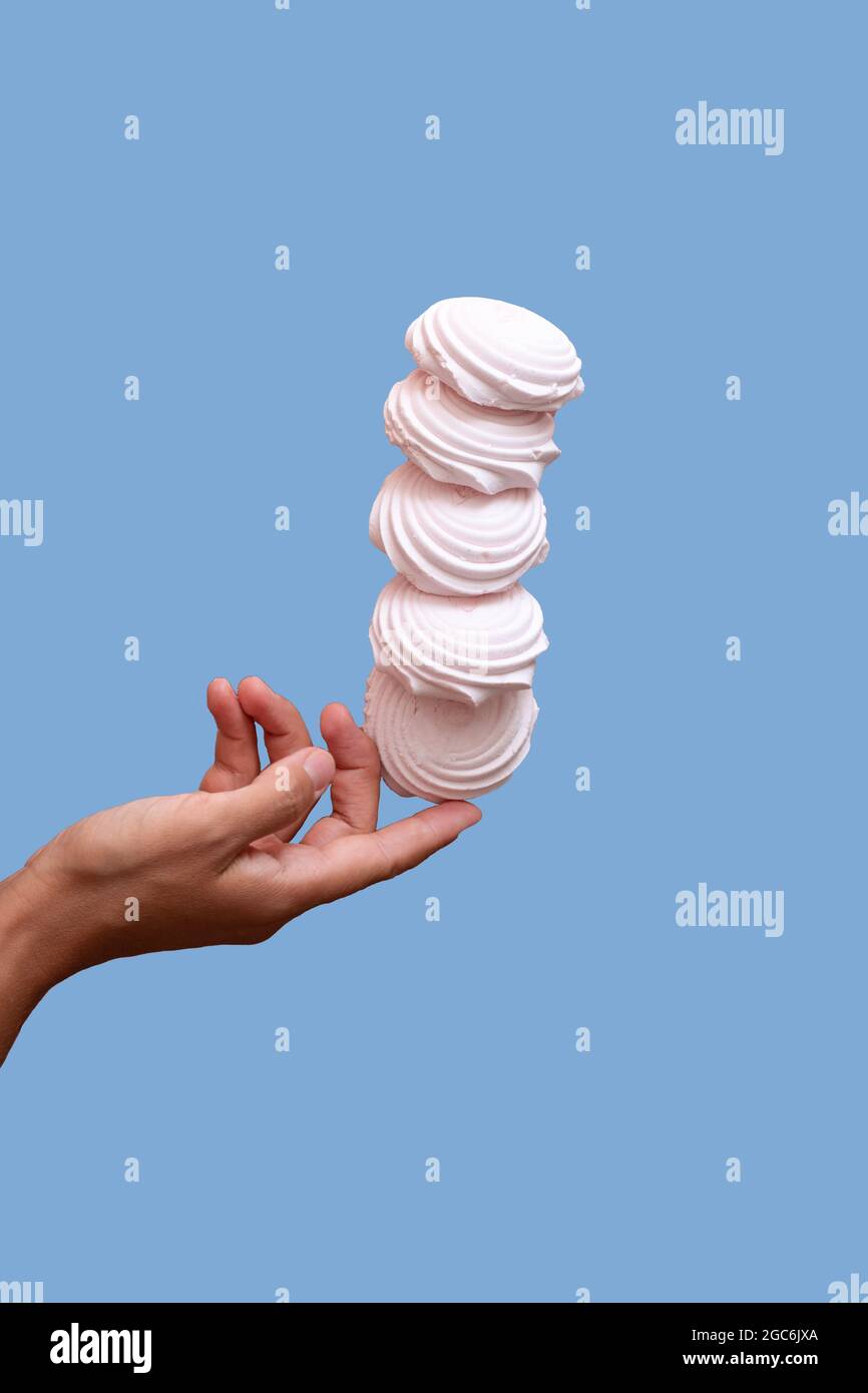 marshmallow floating in the air under hand against blue background ...