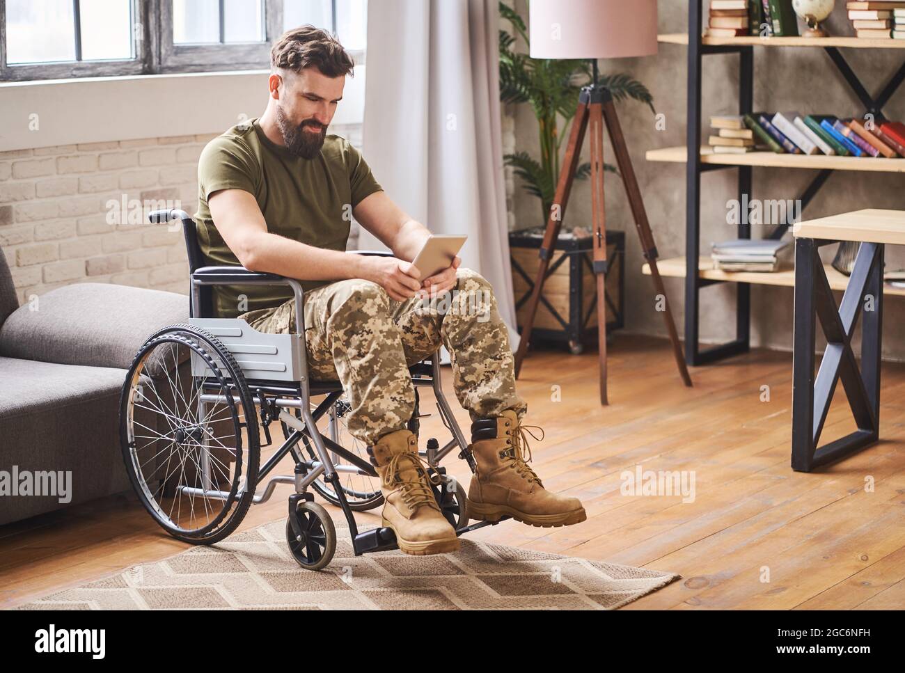 Young veteran sitting in a wheelchair and using a tablet computer Stock ...