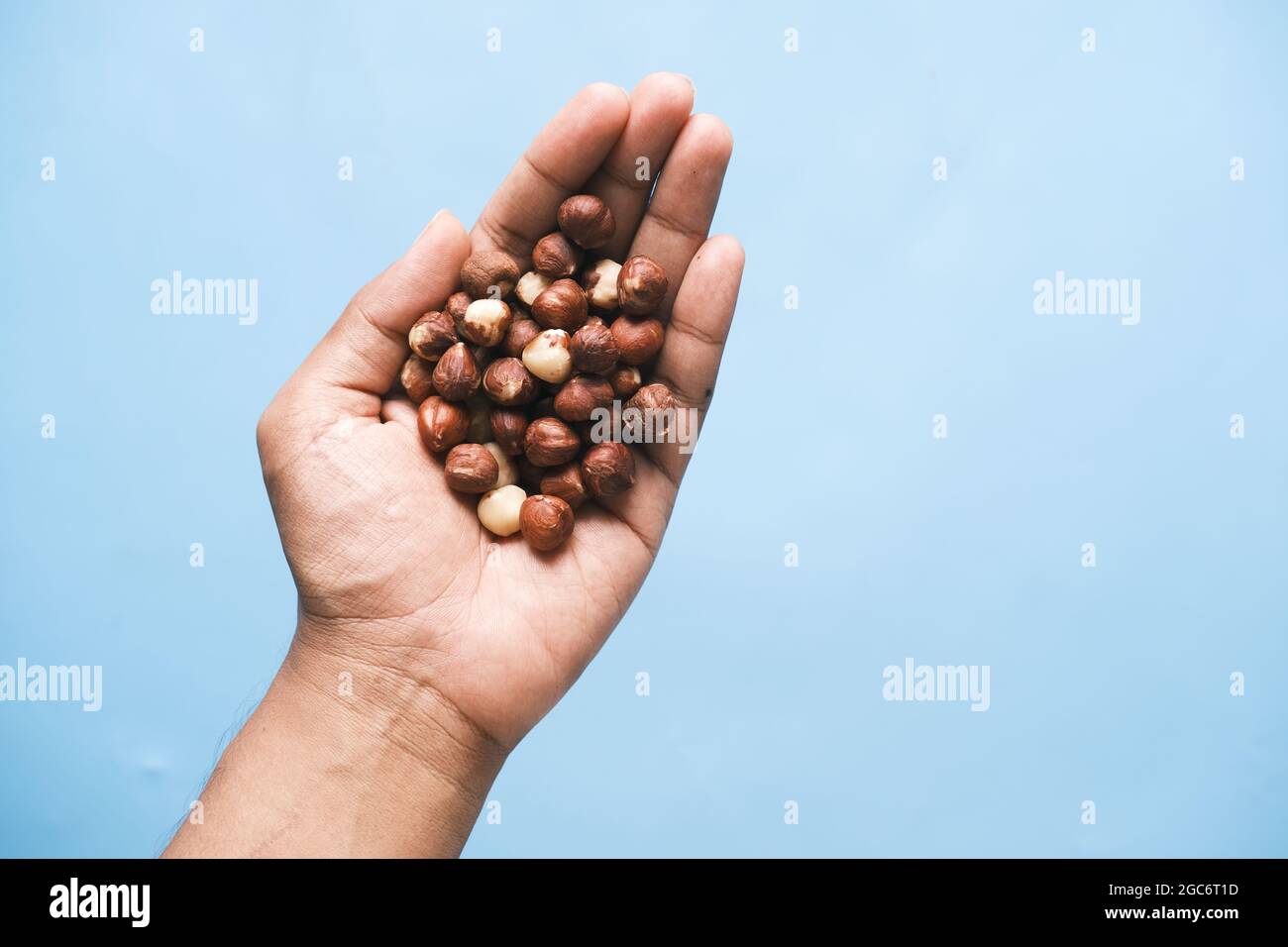 hazelnuts on palm of hand on blue background Stock Photo - Alamy