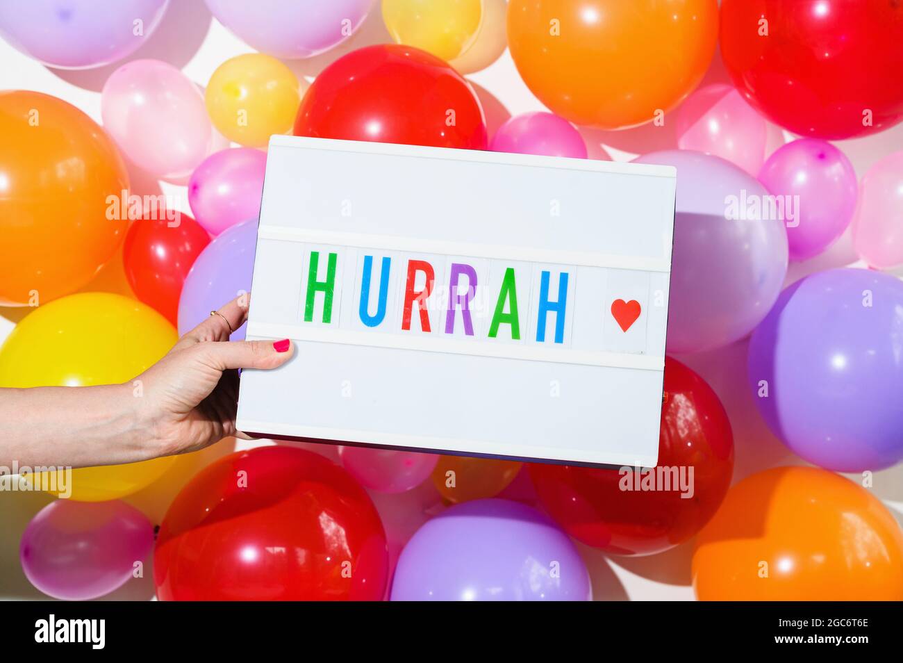 Woman holding sign saying Hurrah in front of balloon wall Stock Photo ...
