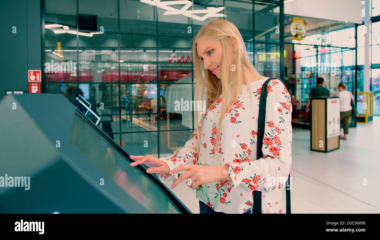 Woman near navigation board in mall. Side view of lovely young female ...