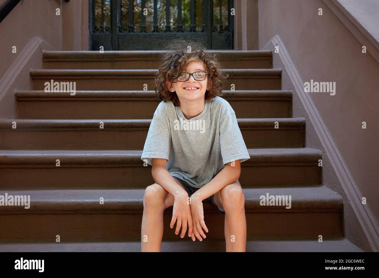 USA, New York, New York City, Boy sitting on steps in front of building ...