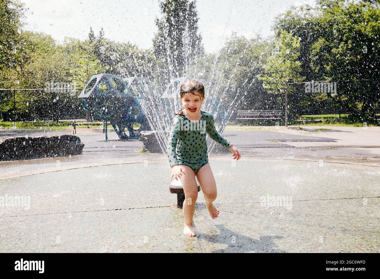 USA, New York, New York City, Girl playing next to water sprinkler on ...