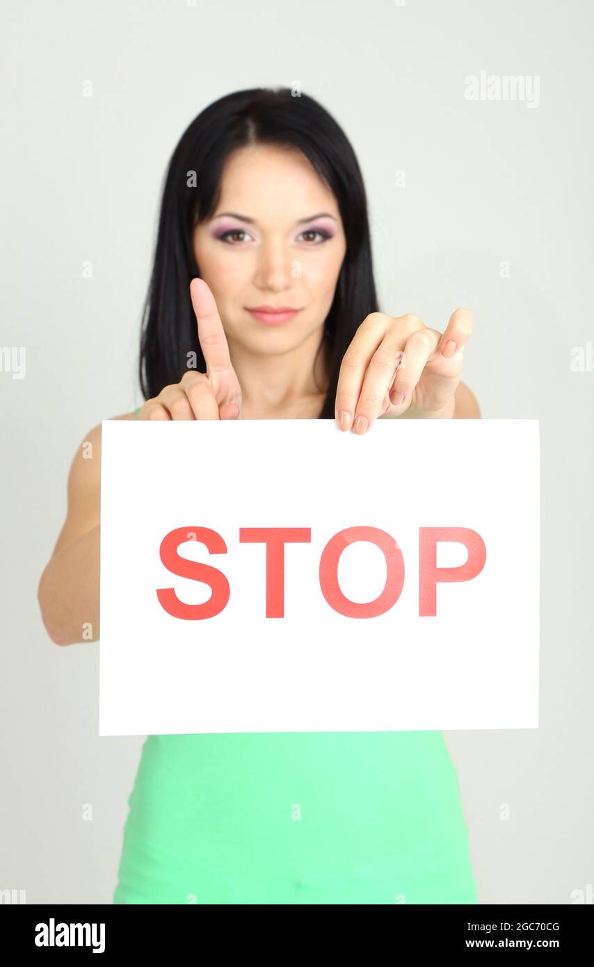 Girl showing stop sign on grey background Stock Photo - Alamy