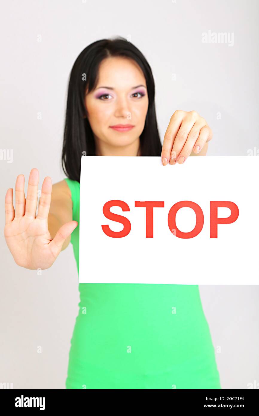 Girl showing stop sign on grey background Stock Photo - Alamy