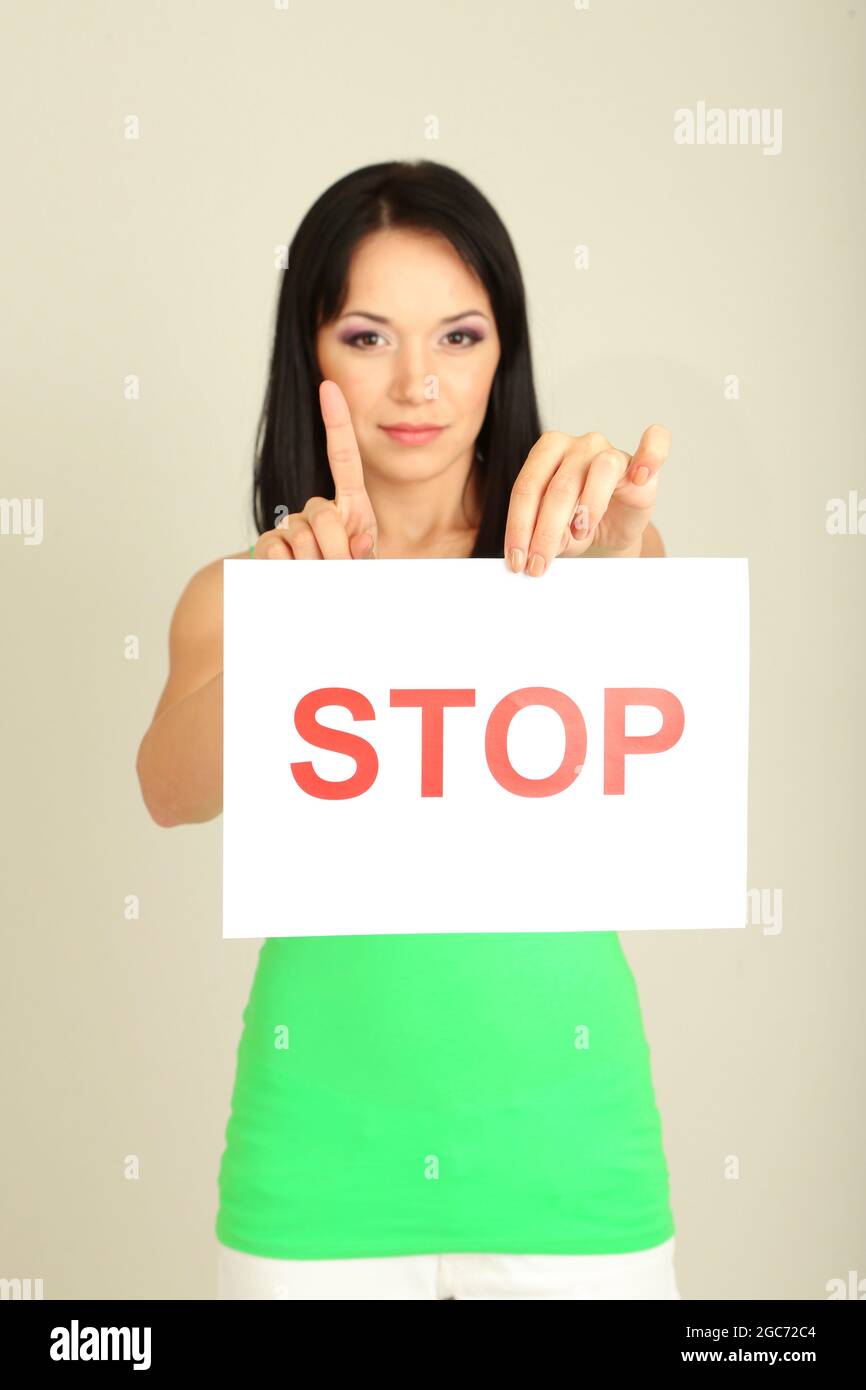 Girl showing stop sign on grey background Stock Photo - Alamy