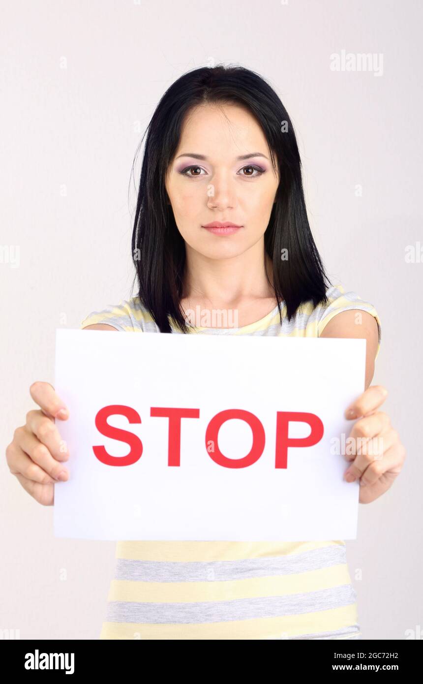 Girl showing stop sign on grey background Stock Photo - Alamy