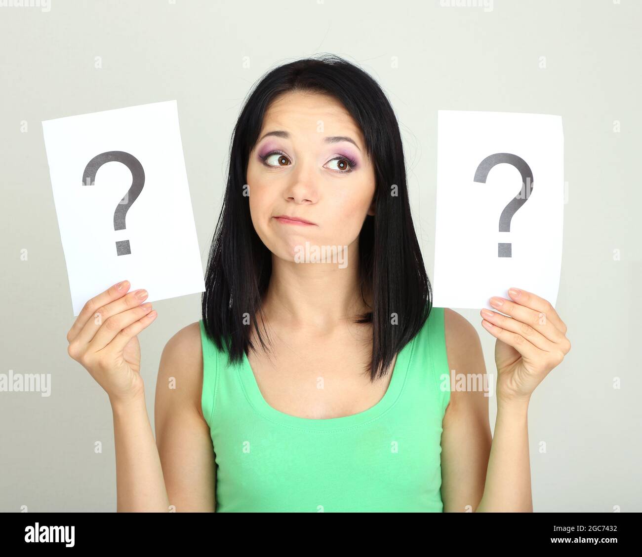 Woman with question marks on grey background Stock Photo - Alamy