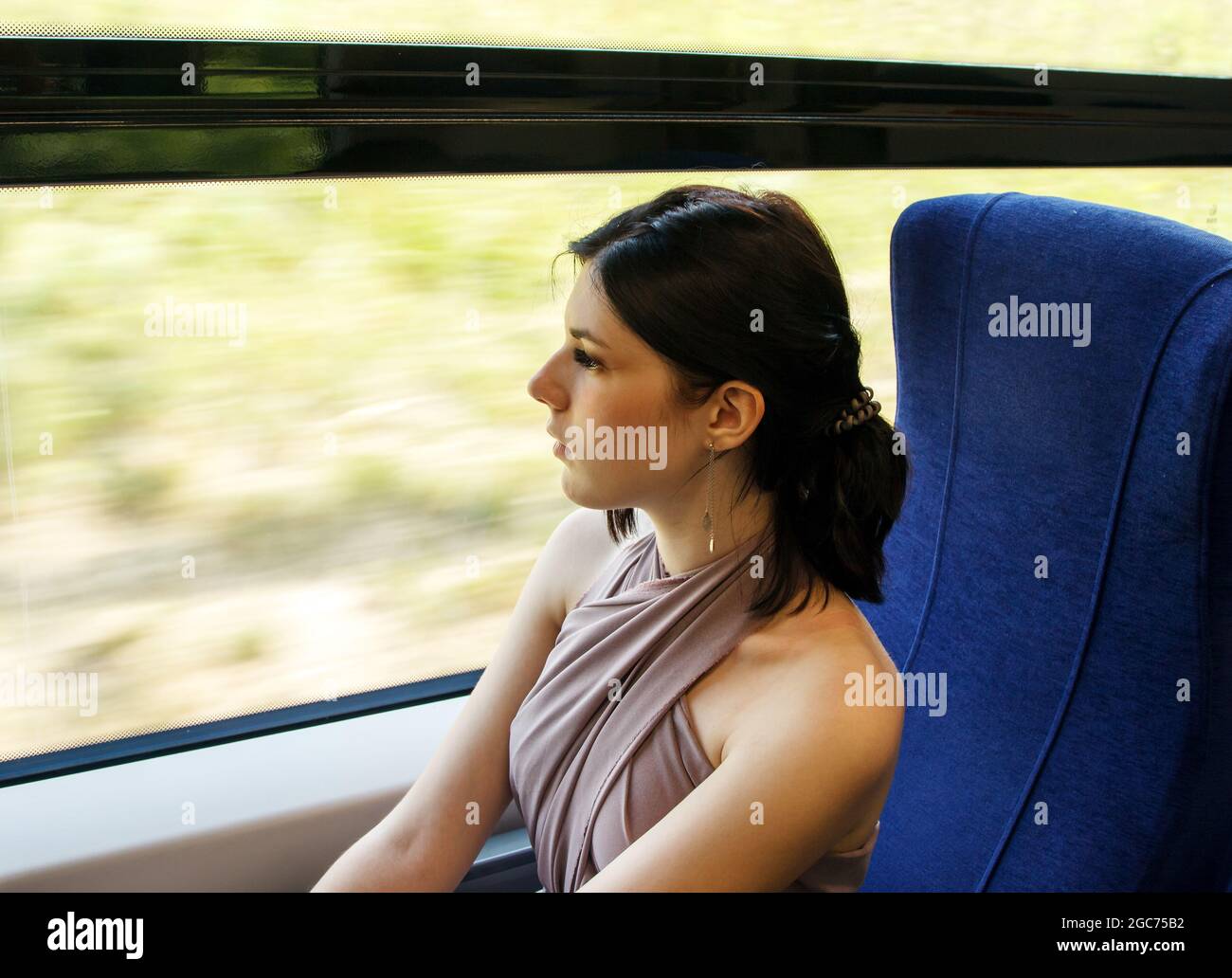 young brunette woman sitting by the window in the train. portrait ...