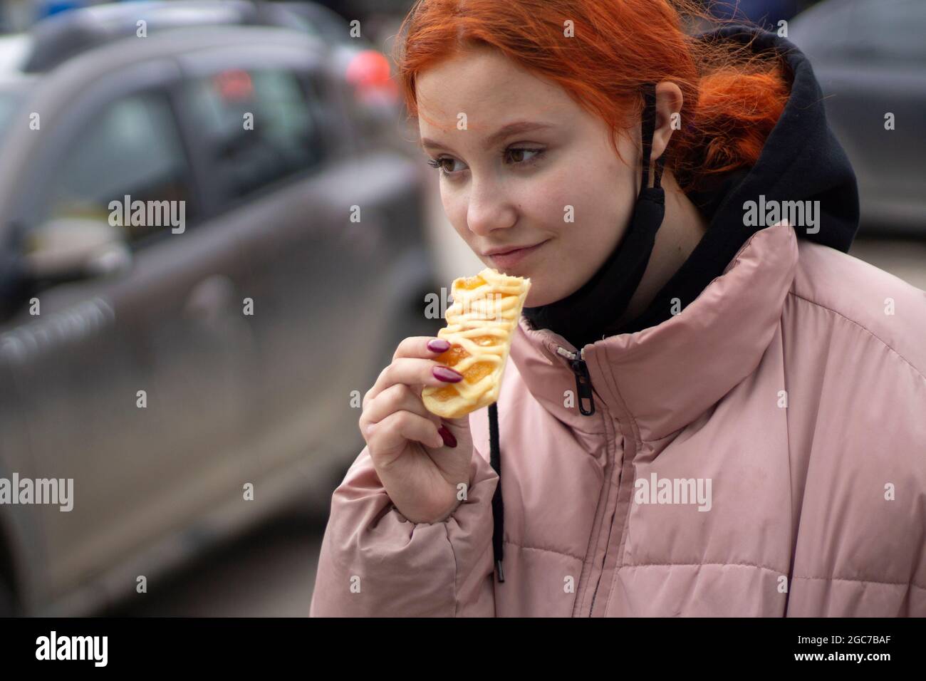 The girl eats flour. The girl is eating a sweet cake on the street ...