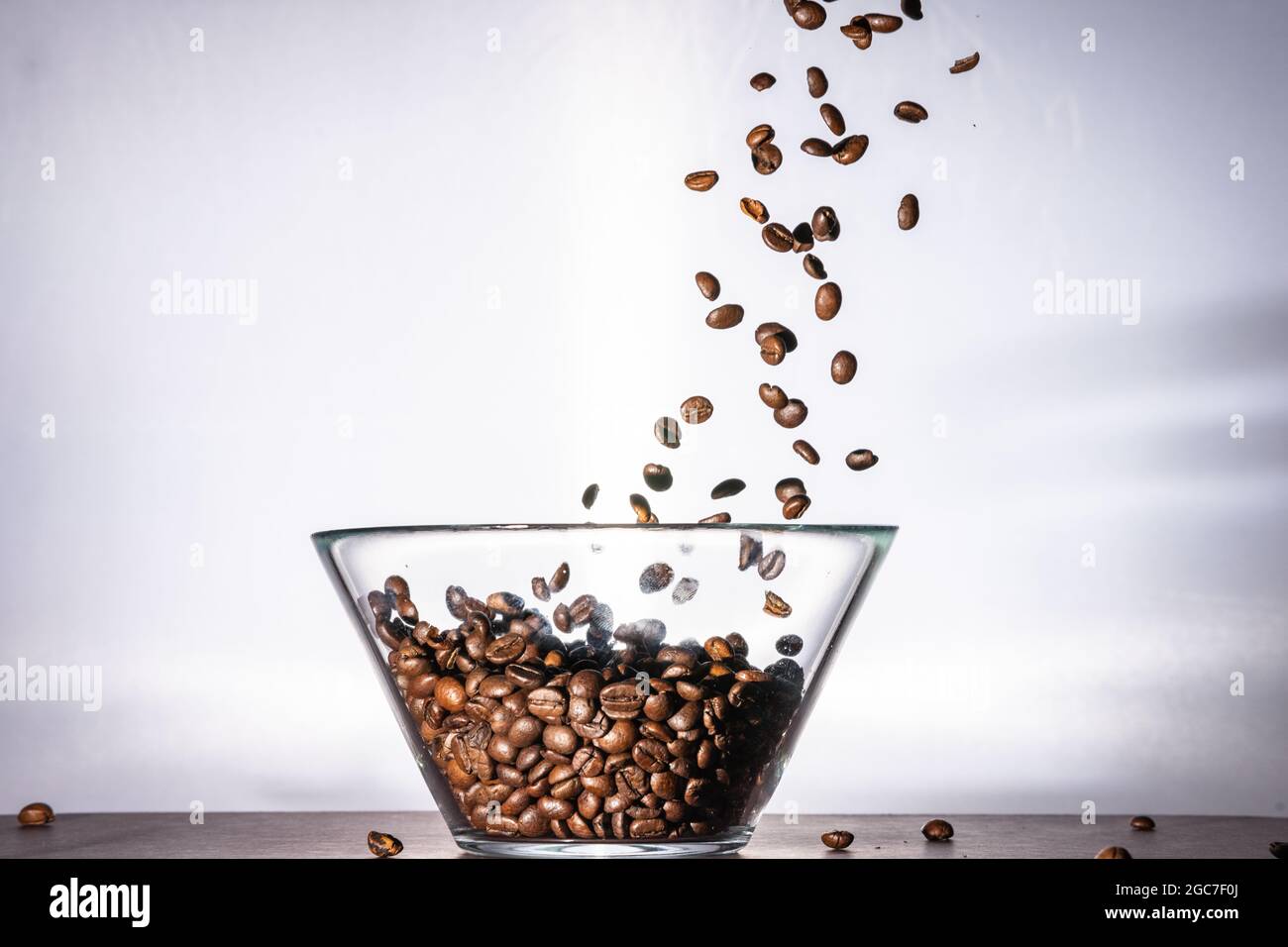 Closeup of black coffee beans pouring into a glass bowl Stock Photo - Alamy