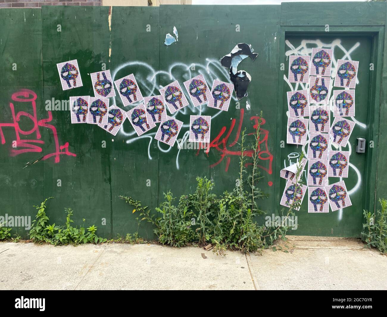 Graffiti and posters on a construction wall by a sidewalk in Brooklyn ...