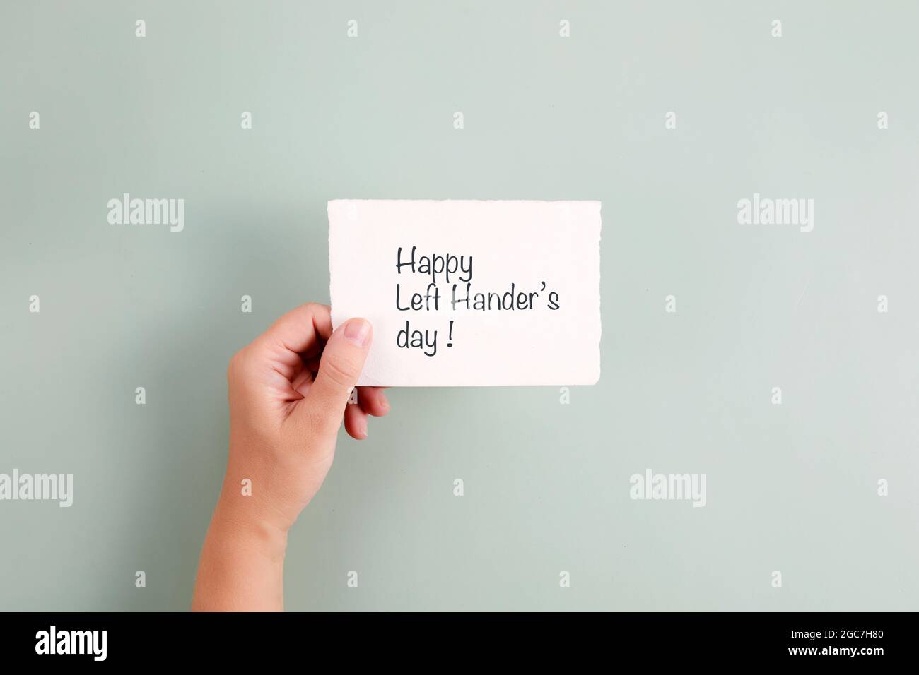 Happy Left Hander's Day. Left hand hold white paper card and writing ...
