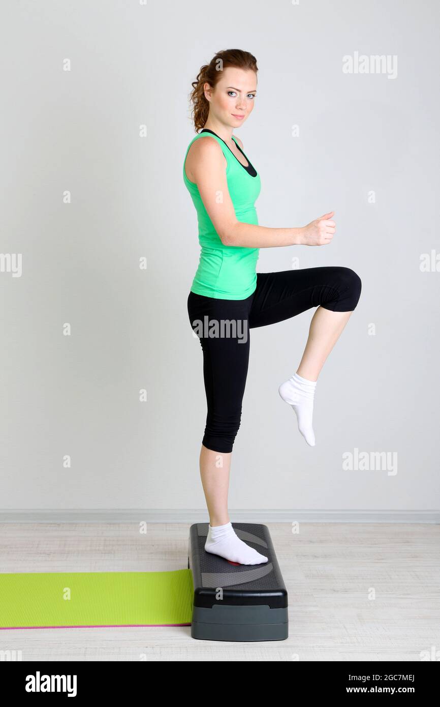 Beautiful young woman exercises on stepper Stock Photo - Alamy