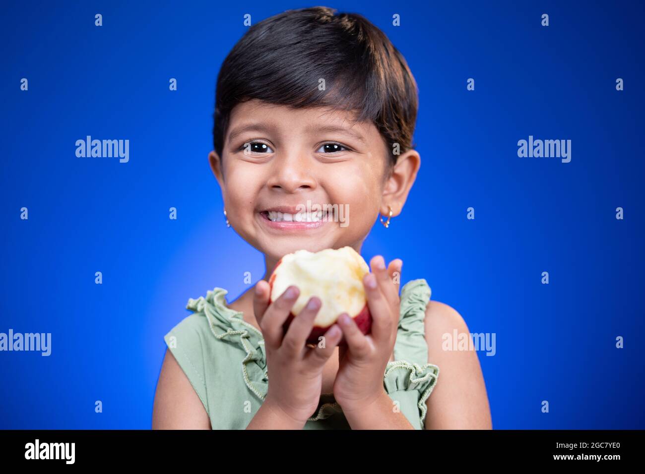 Portrait of girl kid holding apple on blue background - concept of ...