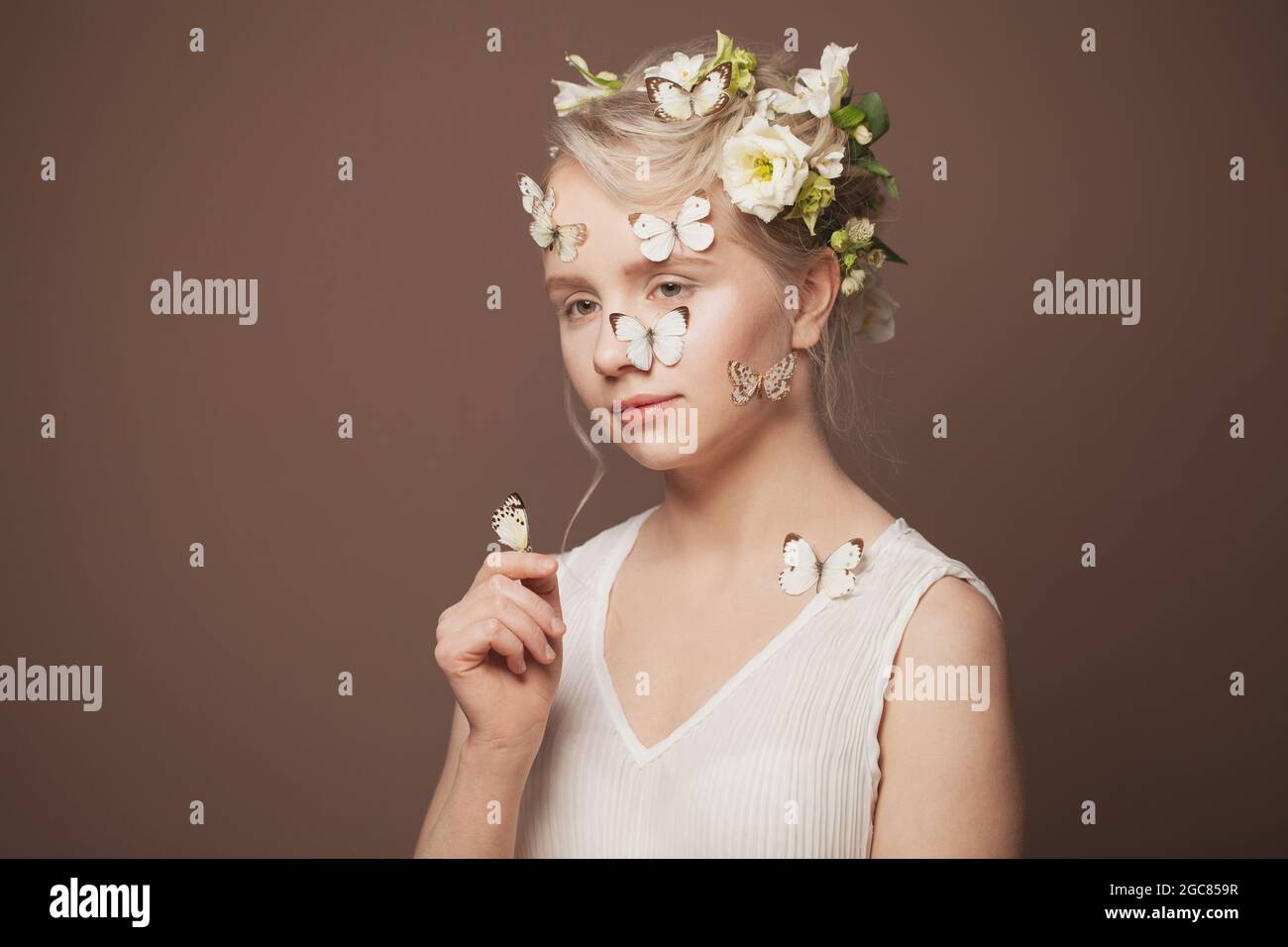 Beautiful young woman in white cloth holds white butterflies and ...