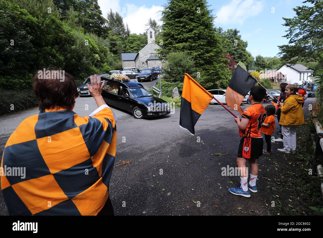 Members of St Colum's GAA club line up as the coffin of Father Con ...