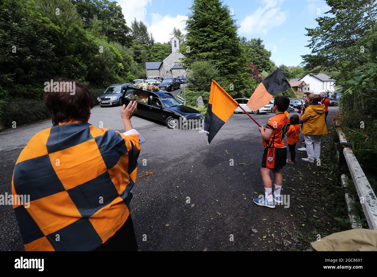 Members of St Colum's GAA club line up as the coffin of Father Con ...