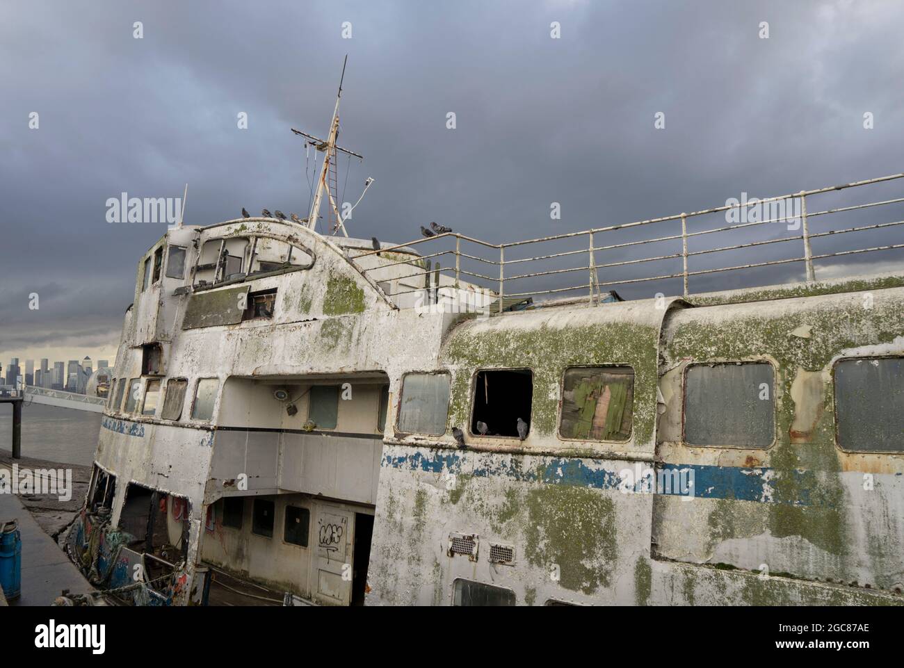 Rusty ship hull of old Mersey ferry by river Thames barrier opposite ...