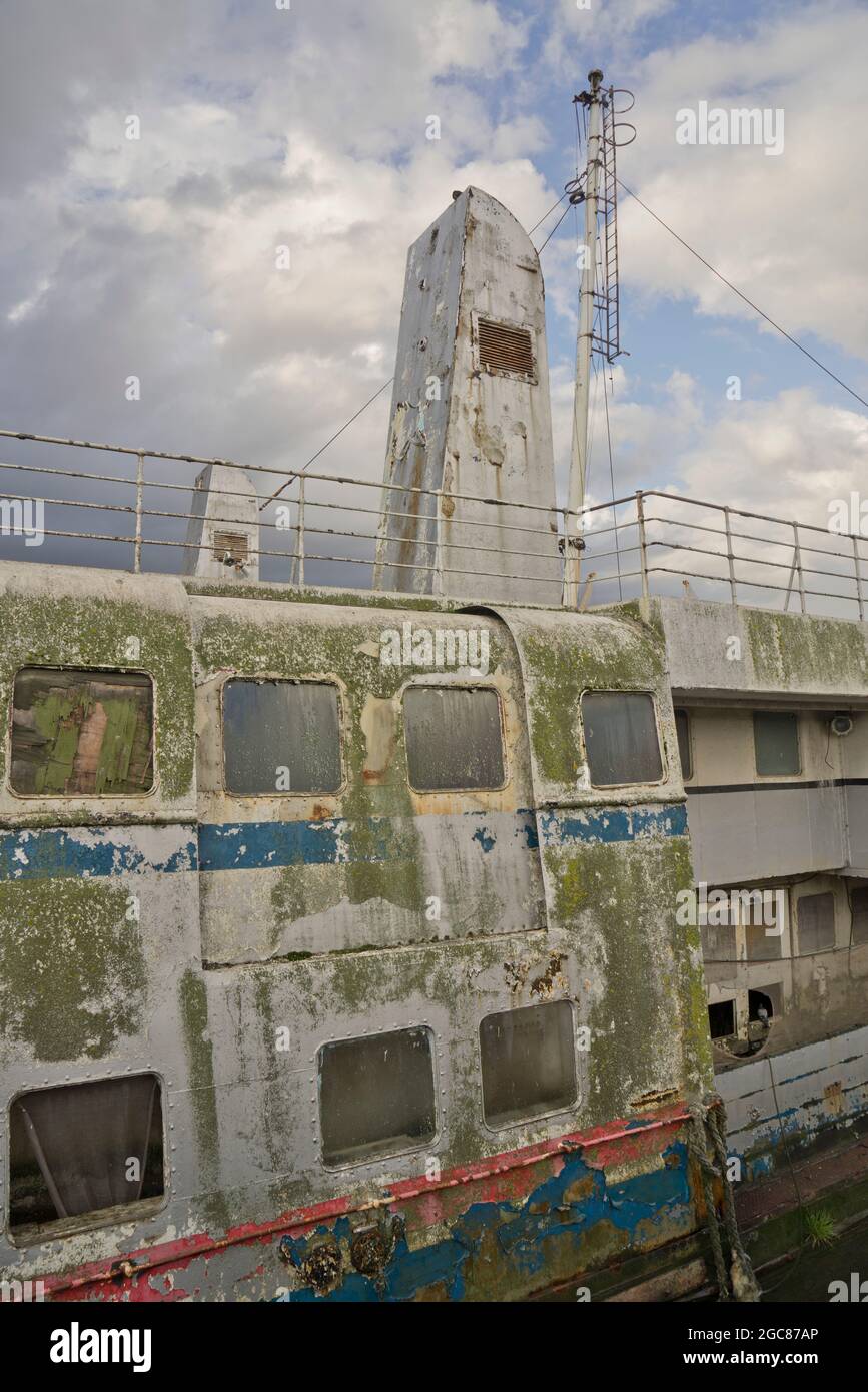 Rusty ship hull of old Mersey ferry by river Thames barrier opposite ...