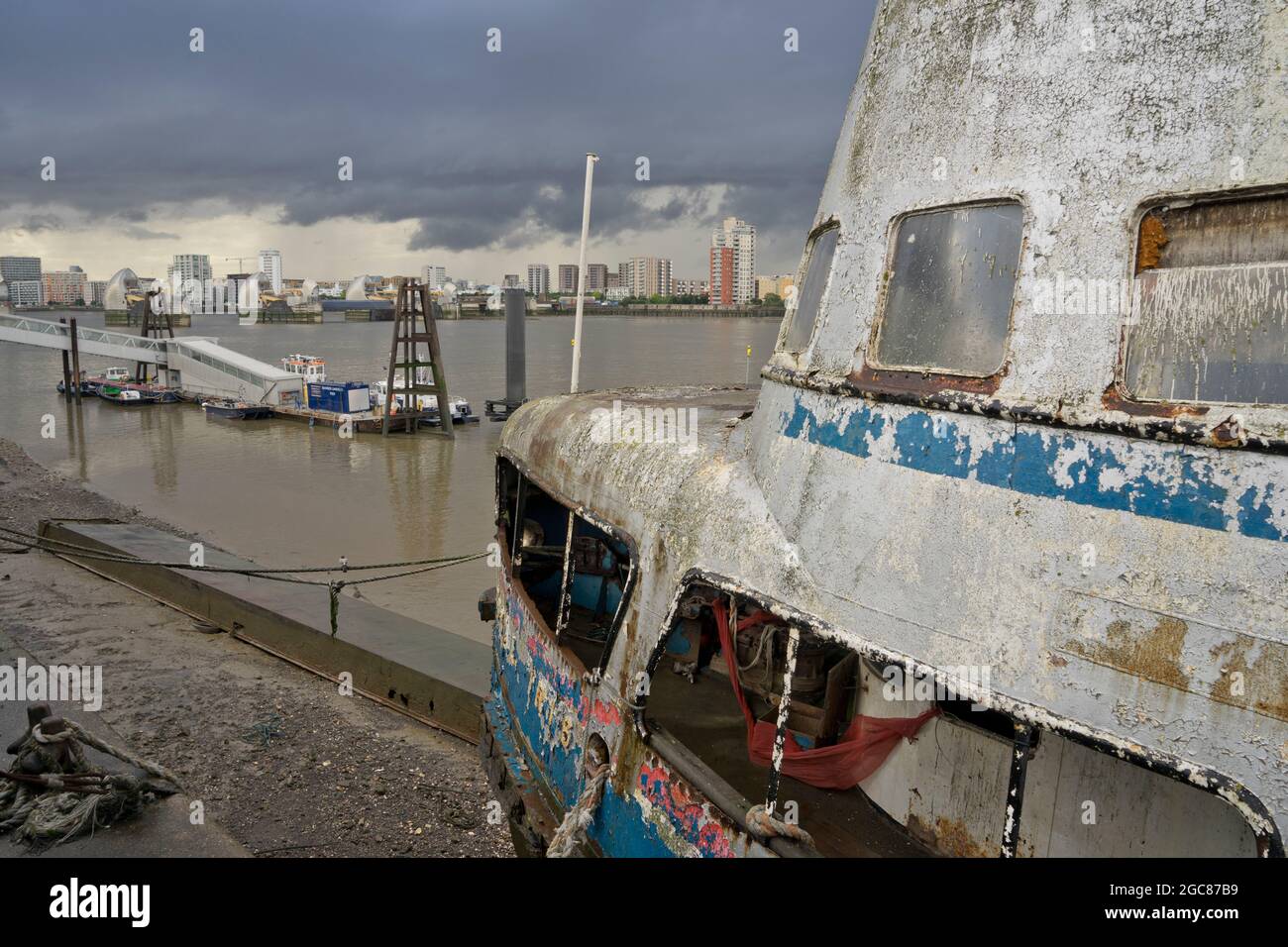 Rusty ship hull of old Mersey ferry by river Thames barrier opposite ...