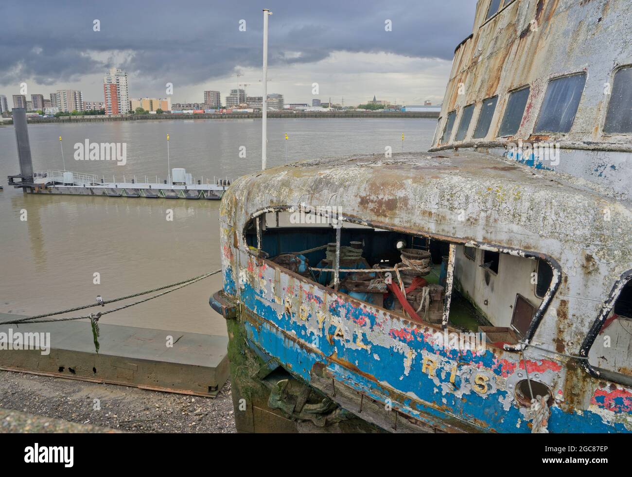 Rusty ship hull of old Mersey ferry by river Thames barrier opposite ...