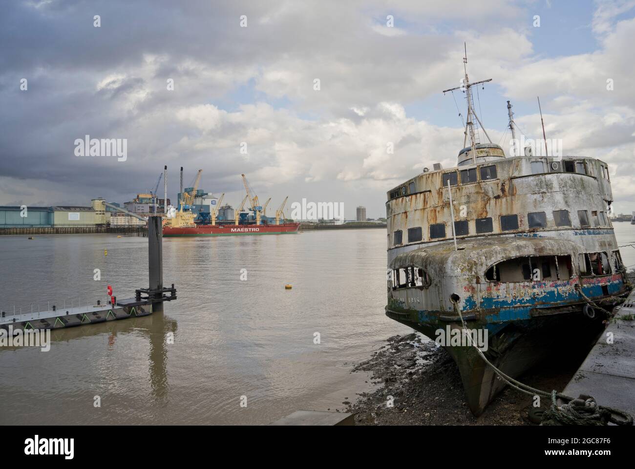 Rusty ship hull of old Mersey ferry by river Thames barrier opposite ...