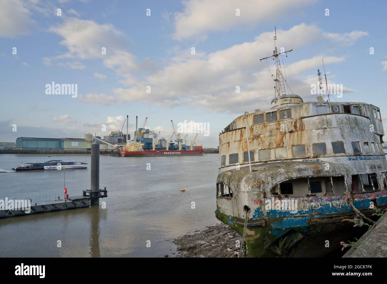 Rusty ship hull of old Mersey ferry by river Thames barrier opposite ...
