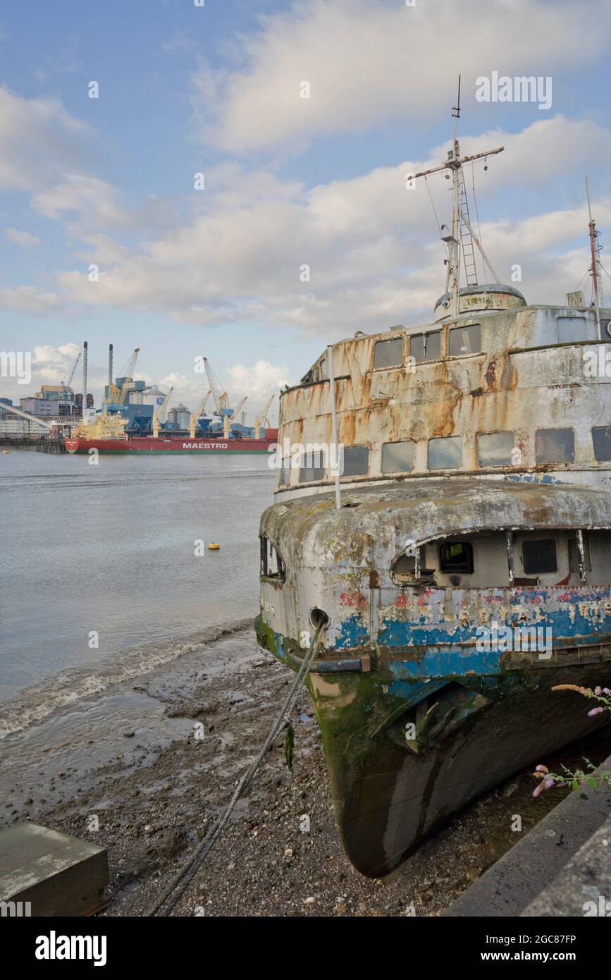 Rusty ship hull of old Mersey ferry by river Thames barrier opposite ...
