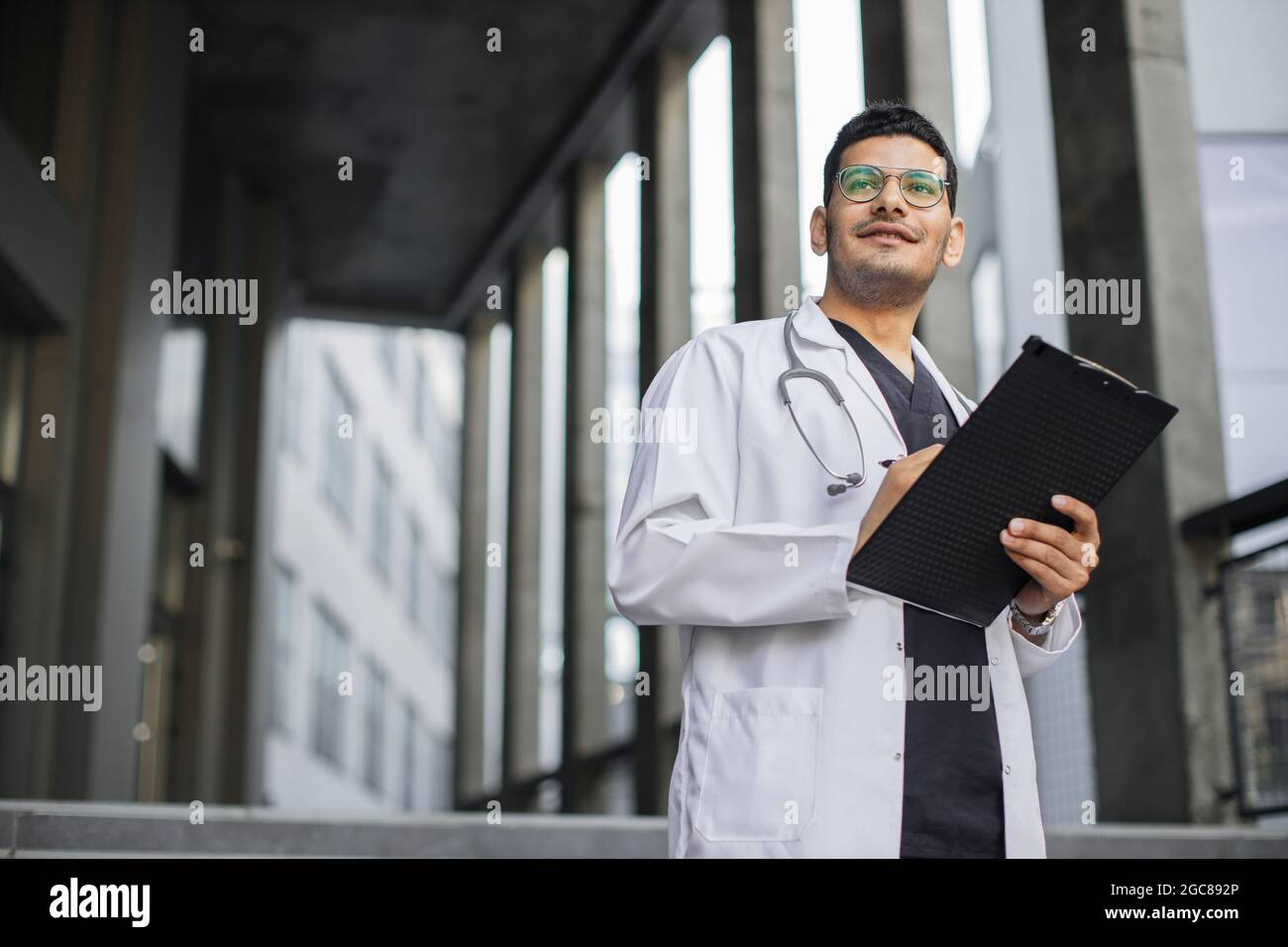Close up portrait of pensive professional male Arab doctor writing RX ...