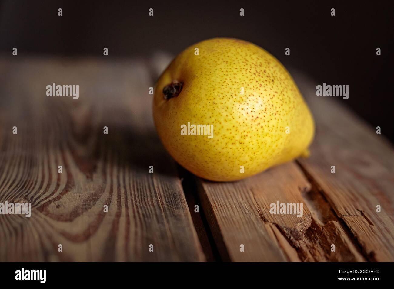 Juicy yellow pear on a wooden background from old boards in a low key ...