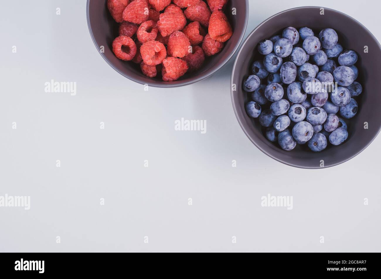 Bowls of raspberries and blueberries isolated on a white background ...