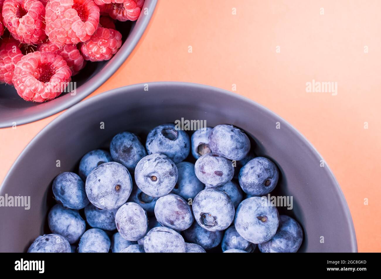 Bowls of fresh blueberries and raspberries isolated on a beige ...