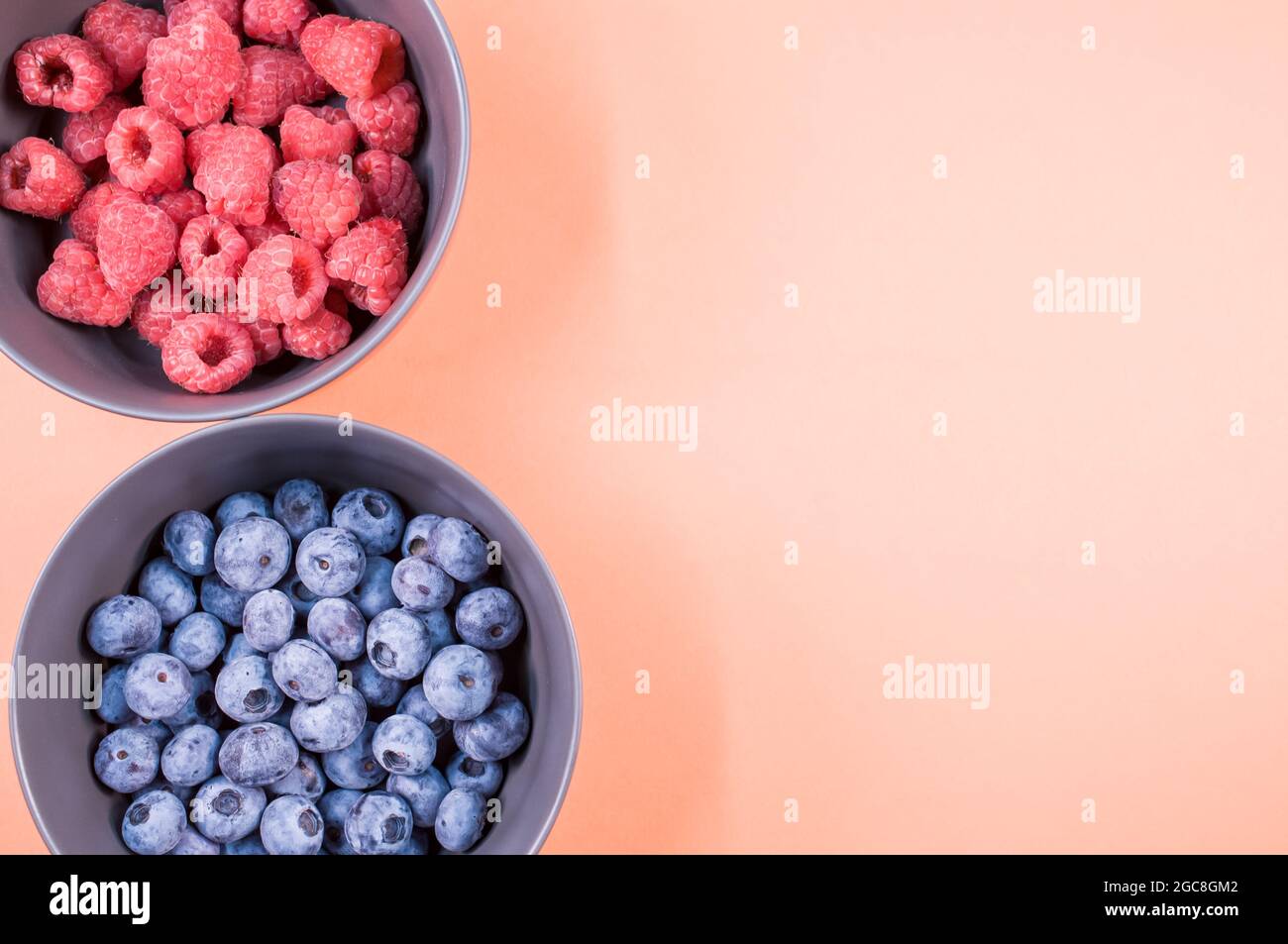 Bowls of fresh blueberries and raspberries isolated on a beige ...