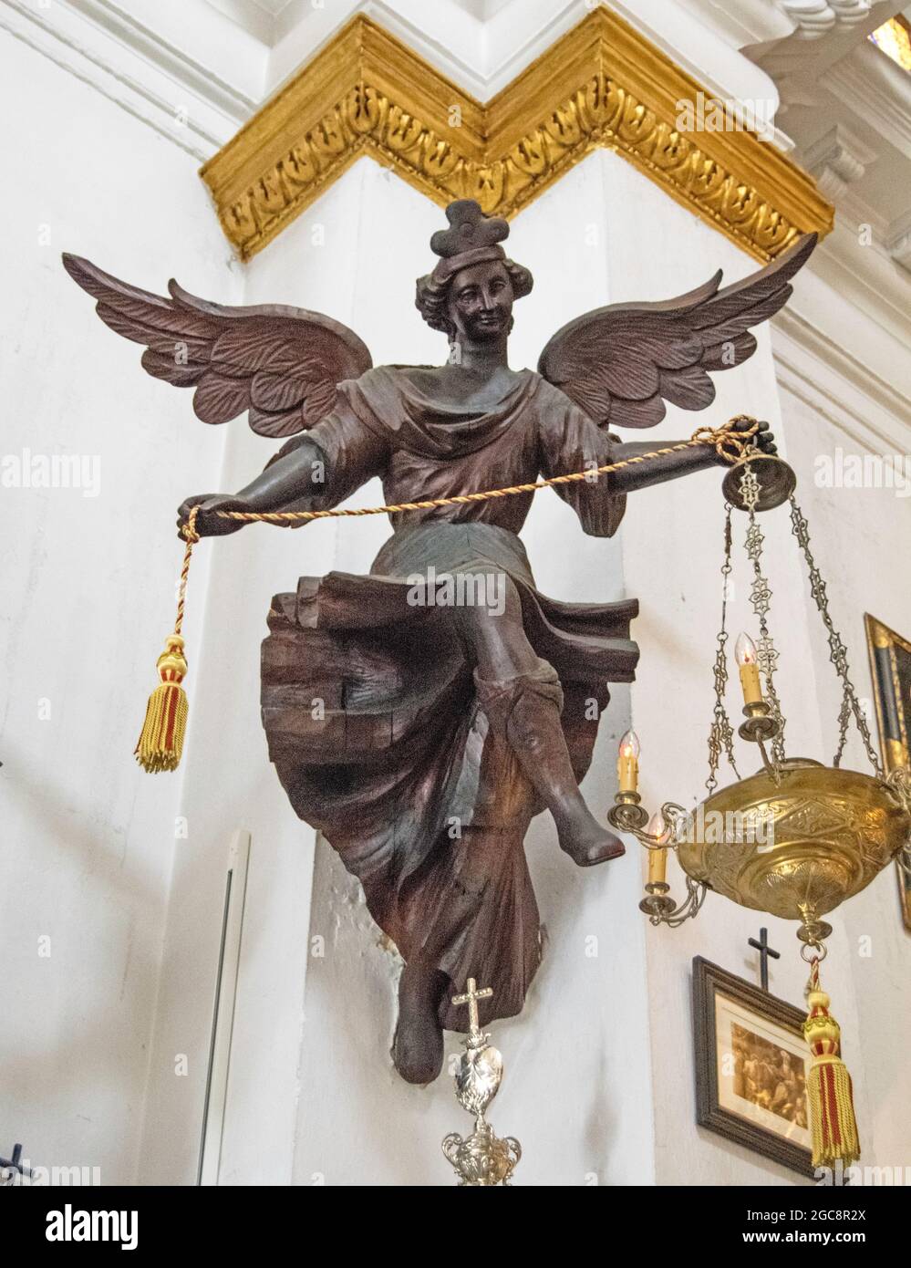 Figure of a bronze angel hanging on the side of the altar of a church ...