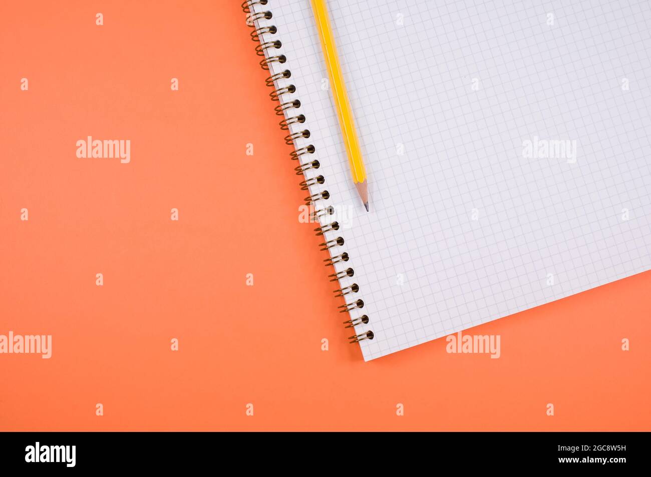 Grid notebook and a pencil isolated on an orange background with free ...