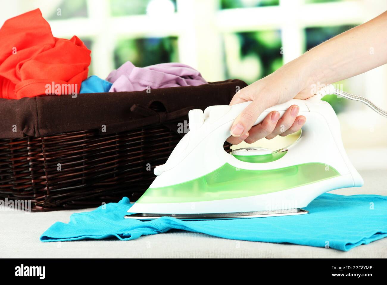Woman's hand ironing clothes, on bright background Stock Photo - Alamy