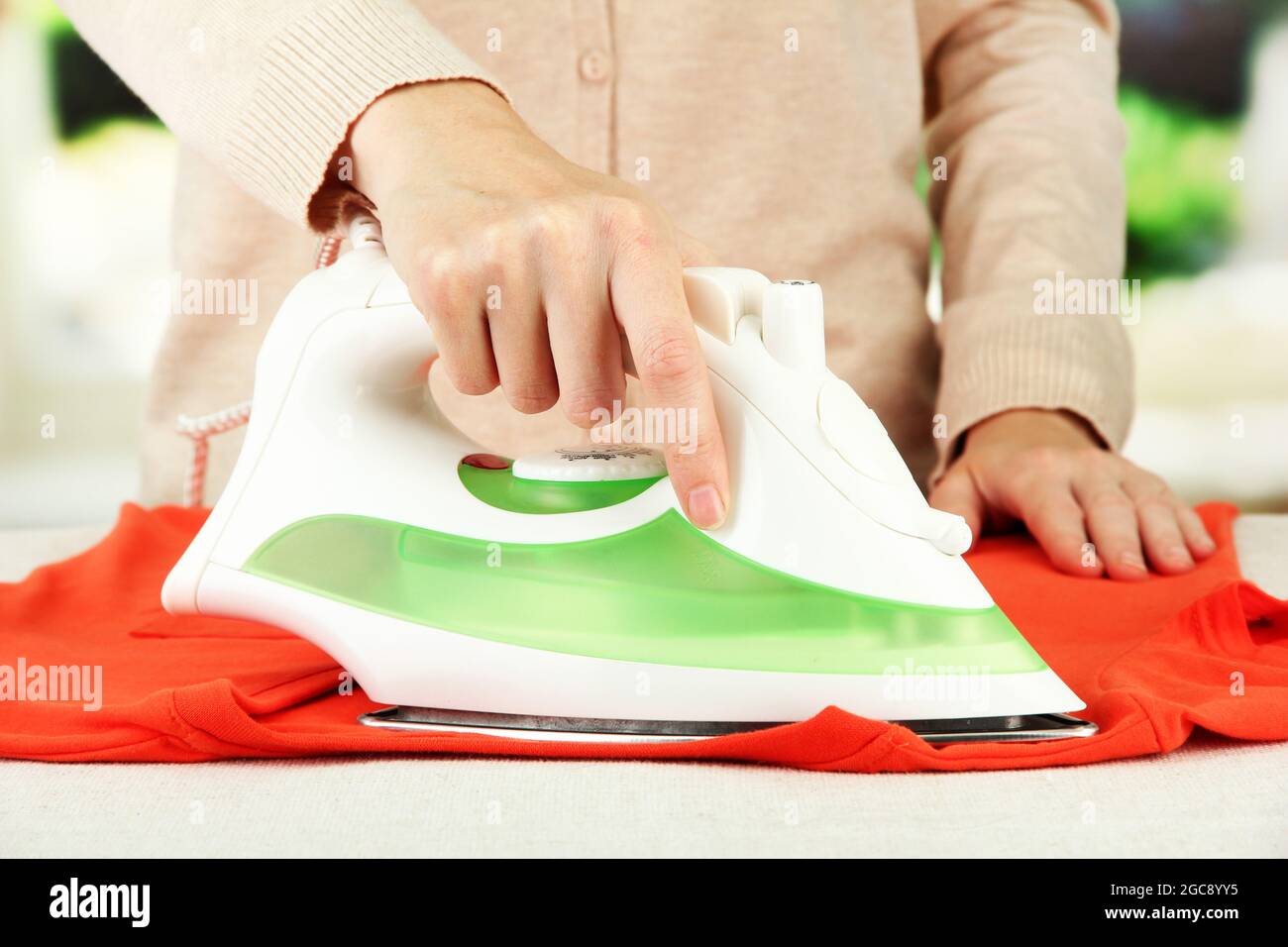 Woman's hand ironing clothes, on bright background Stock Photo - Alamy
