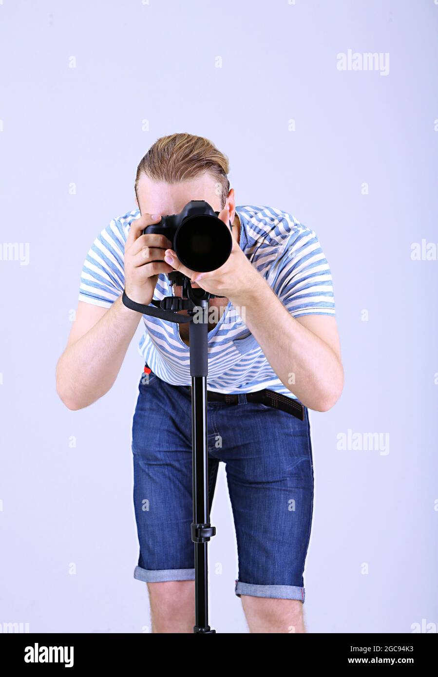 Handsome photographer with camera on monopod, on gray background Stock ...