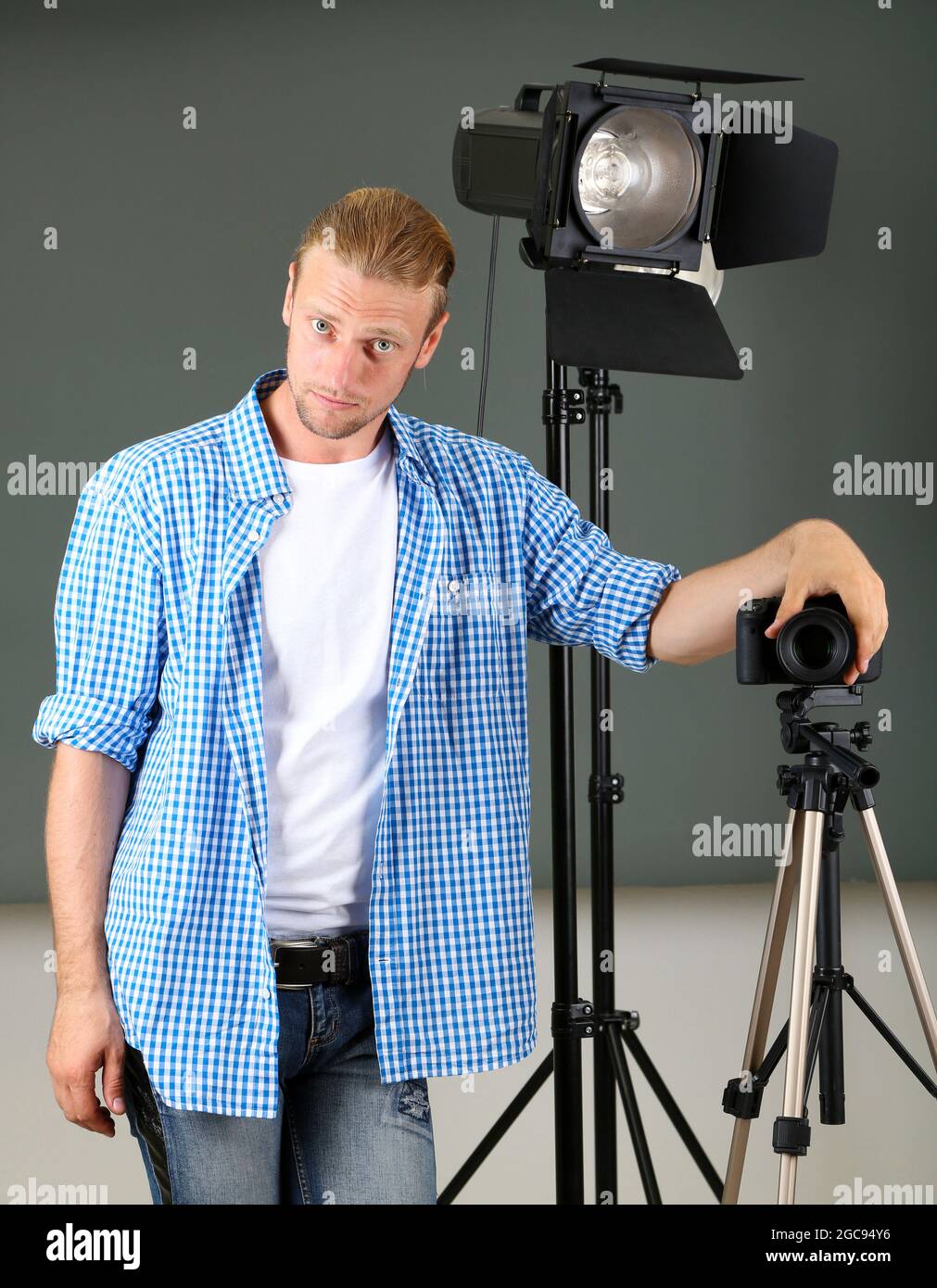 Handsome photographer with camera at working, on photo studio ...
