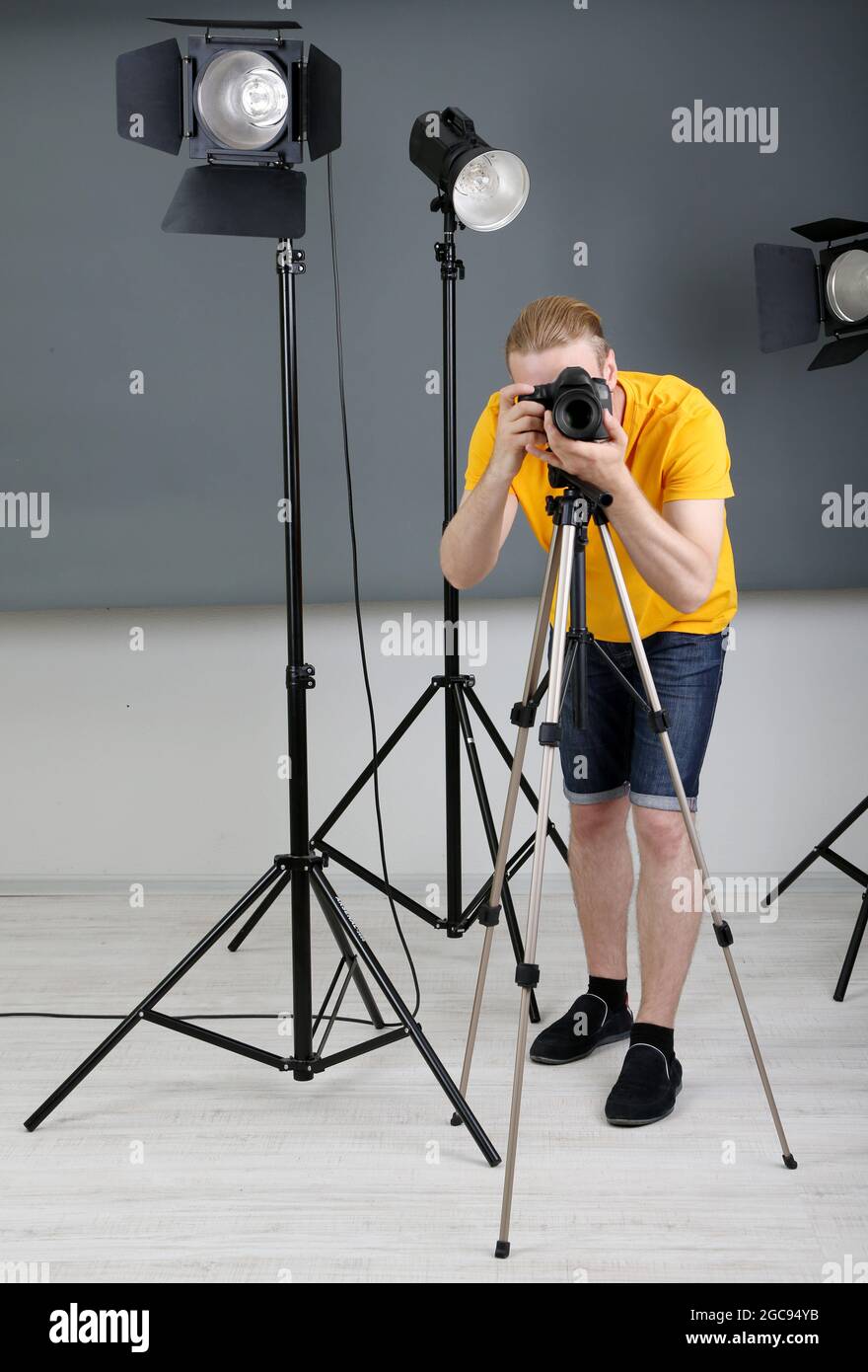Handsome photographer with camera at working, on photo studio ...