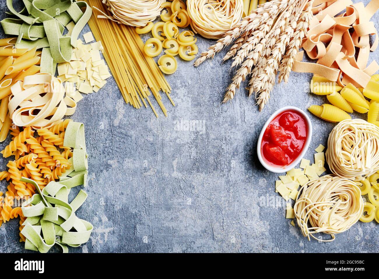 Mixed types and shapes of italian pasta on grey stone, background. Copy ...