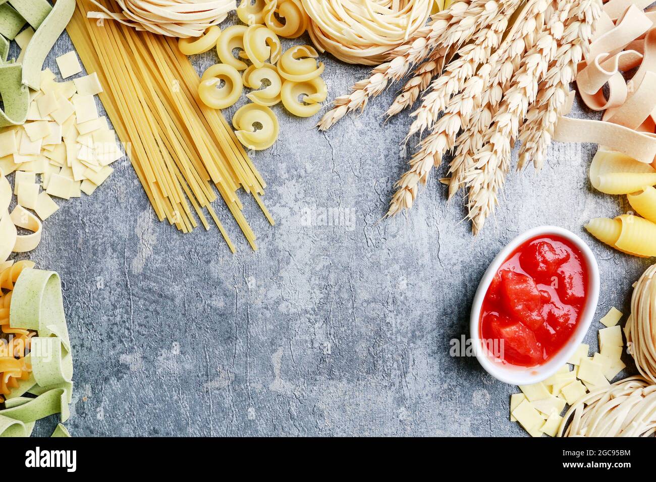Mixed types and shapes of italian pasta on grey stone, background. Copy ...
