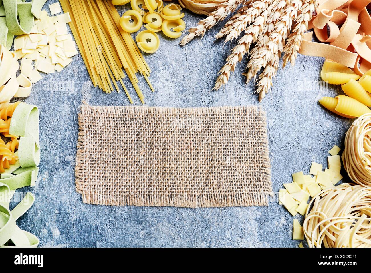 Mixed types and shapes of italian pasta on grey stone, background. Copy ...