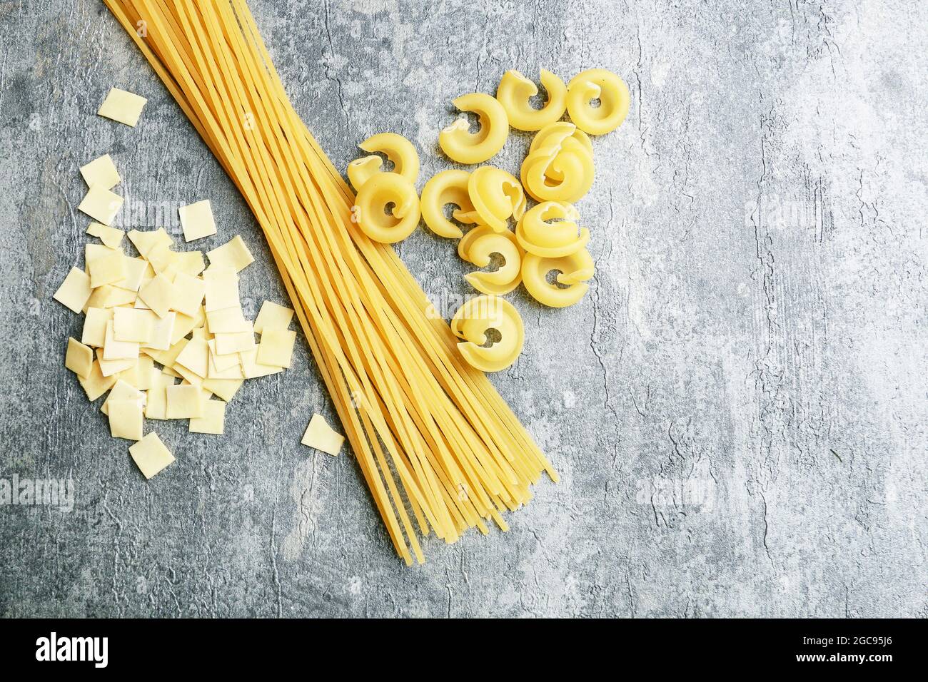 Mixed types and shapes of italian pasta on grey stone, background. Copy ...