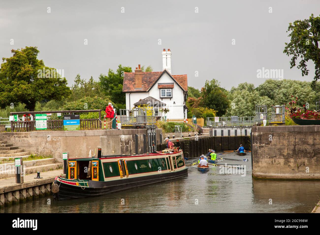 Canal narrow boat and people in rowing boats passing through the locks ...