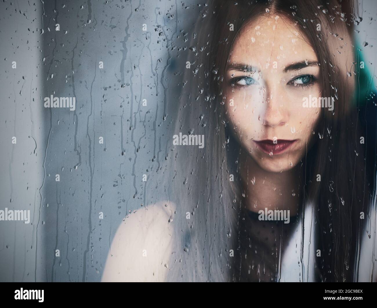 Pretty woman behind wet glass Stock Photo - Alamy