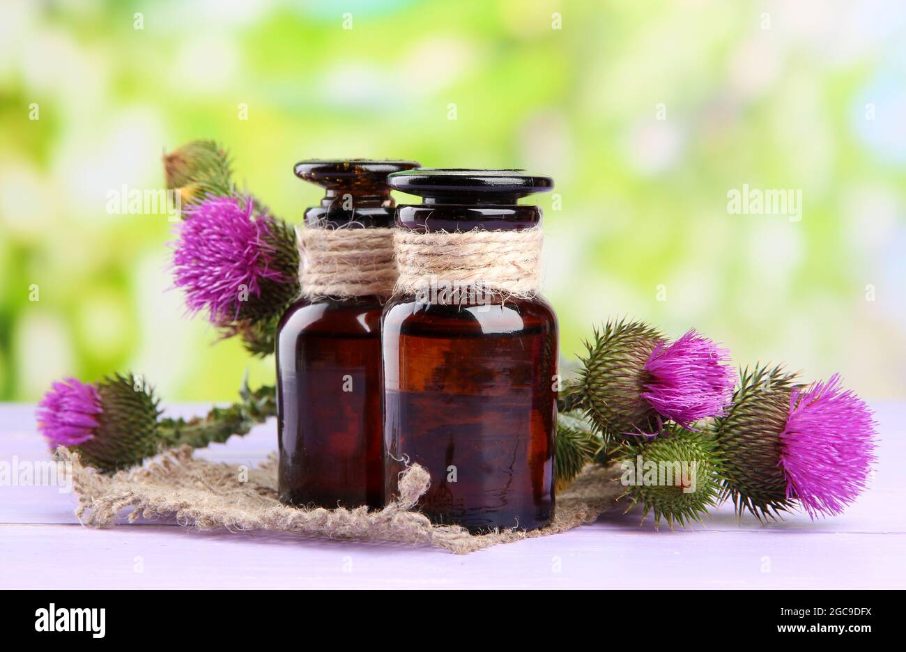 Medicine bottles with thistle flowers on nature background Stock Photo ...