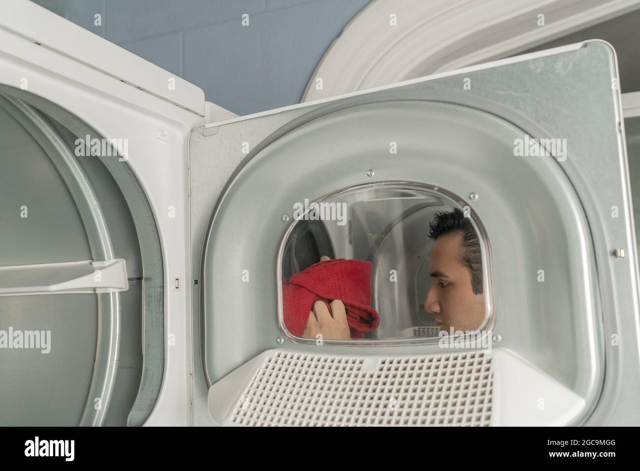 View through the washing machine door of a laundry worker putting ...