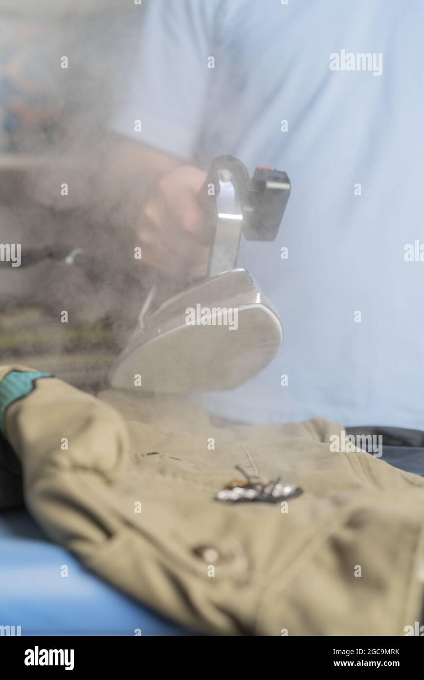 Vertical shot of laundry male worker steam ironing clothes Stock Photo ...